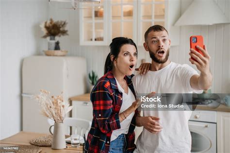 충격을 받은 젊은 성인 백인 커플은 믿을 수 없는 소식에 놀란 눈과 입을 크게 벌린 채 전화기 화면을 바라본다 겁에 질린 남자는 스마트폰 홈에서 아내의 속보를 보여준다 믿을