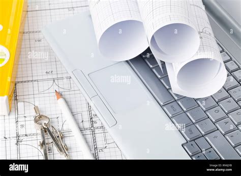 Rolls Of Architectural Blueprint House Building Plans On Laptop Computer Keyboard With Pencil