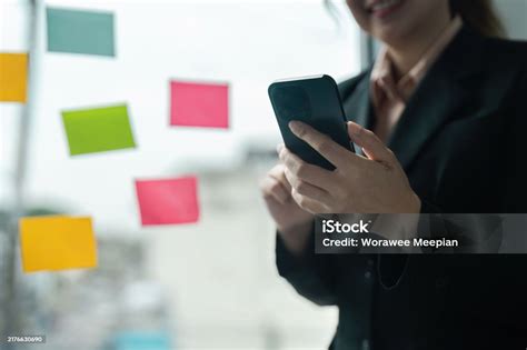 유리 벽에 다채로운 스티커 메모가 있는 현대 사무실에서 스마트폰을 사용하는 전문 사업가 계획에 대한 스톡 사진 및 기타 이미지 계획 사형 집행인 Brand Name