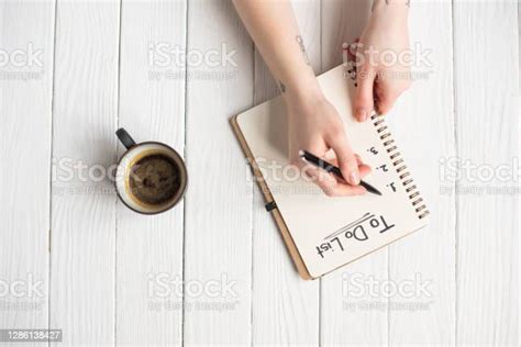 나무 배경에 커피 한 잔 근처 목록 글자를 할 수 있는 노트북에 쓰는 여성의 자른 보기 20 24세에 대한 스톡 사진 및 기타 이미지 20 24세 메모장 목재 재료