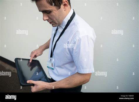 A Young White Man Has A Computer Ipad Tablet And Stands With A White Short Sleeved Shirt And