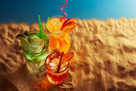 해변에서 오렌지와 녹색 칵테일 모래 위에 얼음 오렌지 민트 라임이 있는 알코올 음료 배경에 일몰 바다와 하늘 유리 근처의 텍스트를 위한 공간과 여유 공간을 복사합니다 0명에