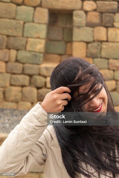 잉카 스타일의 벽 앞에서 얼굴의 일부를 덮고 있는 머리카락을 가진 웃는 여성의 초상화 20 29세에 대한 스톡 사진 및 기타 이미지 20 29세 25 29세 30