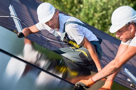 Technicians Carrying Photovoltaic Solar Module While Installing Solar Panel System On Roof Of