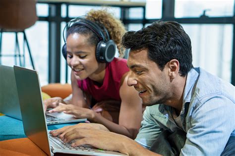 사무실 부부는 노트북 컴퓨터를 사용하여 함께 작업하고 일하는 여자는 헤드폰으로 음악을 듣고 긍정적인 감정 표현에 대한 스톡 사진 및 기타 이미지 긍정적인 감정 표현