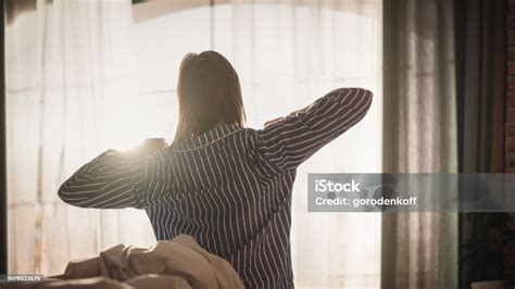 아침에 일어나서 침대에서 뻗어 나오고 태양이 아파트 창문에서 침실로 빛나고 비즈니스 기회 업적 모험을위한 준비를위한 아름다운 젊은 여성 아침에 대한 스톡 사진 및 기타