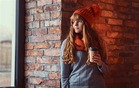 따뜻한 스웨터와 벽돌 벽에 기대어 창문을 보고 커피 한 잔을 들고 모자를 입고 빨간 머리 소녀 12월에 대한 스톡 사진 및 기타 이미지 Istock