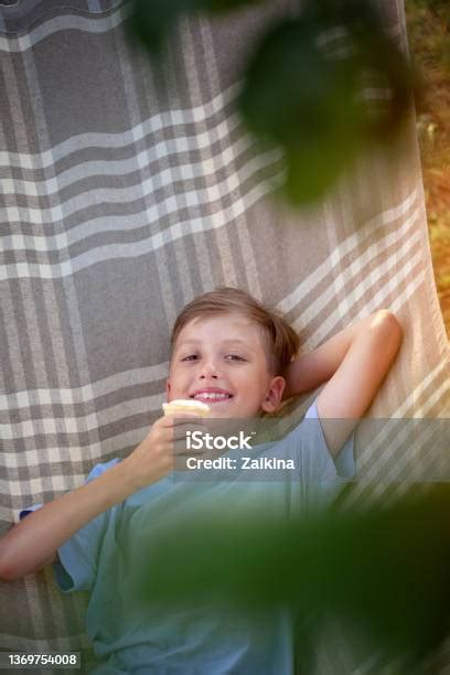 아이스크림을 먹고 뒤뜰이나 야외에서 해먹에서 즐거운 시간을 보내는 귀여운 미소 짓는 백인 소년 여름 더위 속에서 시원하게 지내는 아이 10 11세에 대한 스톡 사진 및 기타