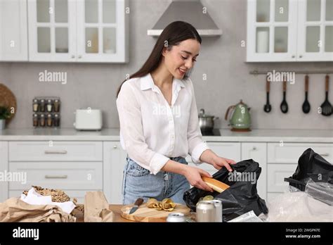 Garbage Sorting Woman Putting Food Waste Into Plastic Bag At Table In Kitchen Stock Photo Alamy