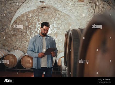 The Winemaker Standing In The Wine Cellar Monitoring The Fermentation
