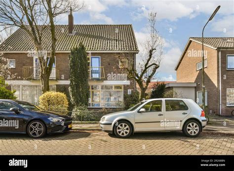 Two Cars Parked Next To Each Other Car In Front Of Some Houses On A