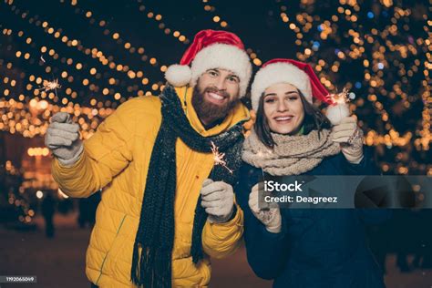 사진 사진 커플 남자 여자 두 사람 Xmas 축 하 공원에서 마술 스파클러를 들고 야외 에서 새해 파티 착용 따뜻한 코트 산타 모자 스카프 장갑 외부 야외에 대한 스톡 사진