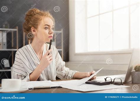 Young Woman Analyzing Printed And Electronic Business Information Stock