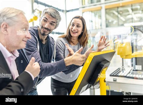 Happy Colleagues Giving Thumbs Up In Robotic Factory Stock Photo Alamy