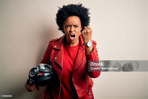 젊은 아프리카계 미국인 Afro 오토바이 여자 곱슬 머리를 들고 오토바이 헬멧 화가 와 화가 주먹 좌절과 분노로 외치는 동안 분노와 공격적인 개념 감정에 대한 스톡 사진 및