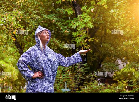 Young Beautiful Blonde Girl In A Blue Raincoat With Patterns Walks In A