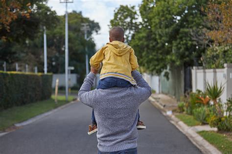 아버지와 아들은 거리에서 걷고 있습니다 성숙한 남자가 어린 소년을 길로 태우고 재미있게 놀고 야외에서 피기 백 타기를 즐기는 뒷모습 아버지에 대한 스톡 사진 및 기타 이미지