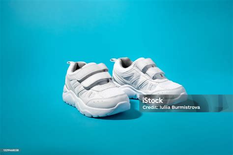 하드 햇빛과 파란색 종이 배경에 쉽게 신발을 신을 수있는 벨크로 패스너와 두 개의 흰색 아이 스포츠 신발의 전면 보기 0명에 대한 스톡 사진 및 기타 이미지 Istock