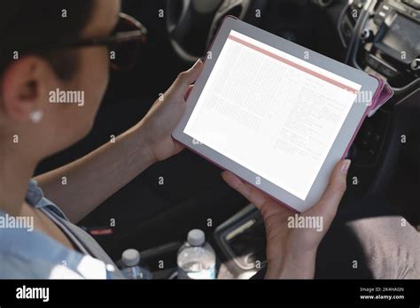 Biracial Female Programmer Sitting In Car Holding Tablet With Copy
