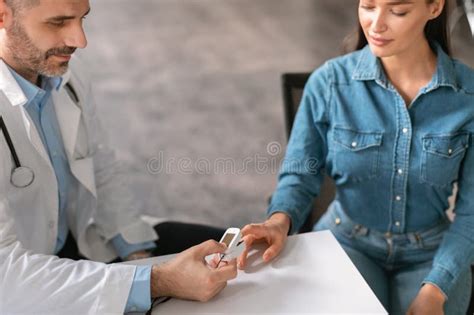 Male Doctor Measuring Oxygen Saturation Level To Female Patient While