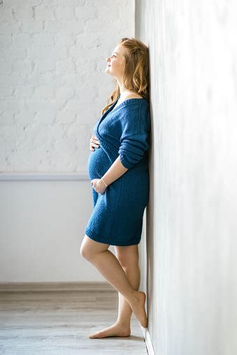 파란 바디콘 드레스를 입은 30주 임신한 여성이 하얀 벽에 머물러 있다 출산 휴가 임신 계획 출산 준비 임신에 대한 스톡 사진 및 기타 이미지 Istock