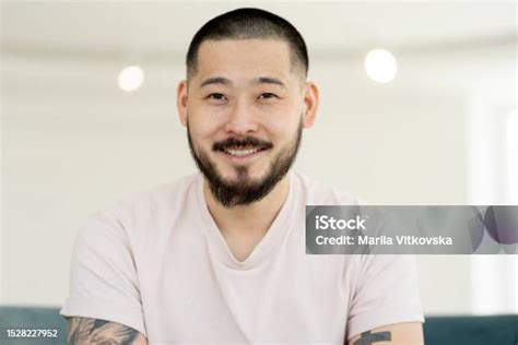 젊은 아시아 남자가 사진을 찍기 위해 포즈를 취하고 카메라를 보고 실내에서 웃고 직장에서 초상화를 클로즈업한다 30 34세에