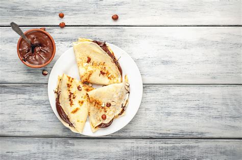 나무 배경에 흰 접시에 초콜릿 스프레드와 헤이즐넛을 사용한 팬케이크 0명에 대한 스톡 사진 및 기타 이미지 0명 갈색