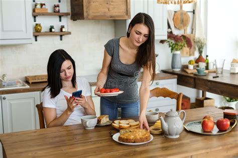 Two Girls Are Drinking Tea With Cake And Sweets At The Table Stock
