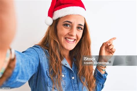크리스마스 모자를 쓰고 셀카를 찍는 젊은 아름다운 빨간 머리 여자는 측면에 손과 손가락으로 가리키는 매우 행복 보여주기에 대한 스톡 사진 및 기타 이미지 Istock