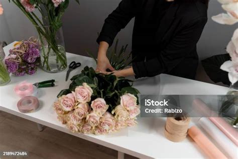 꽃의 꽃다발을 주문에 맞게 배치하는 플로리스트 장미 꽃의 꽃다발을 종이에 싸서 꽃집의 테이블에서 30 34세에 대한 스톡 사진