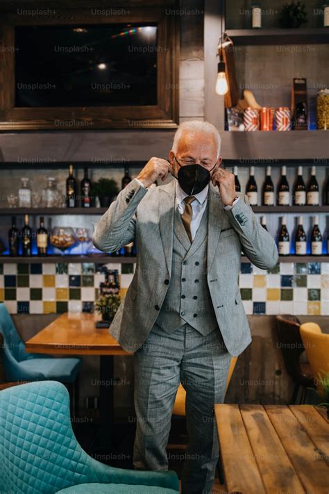 고급 레스토랑에 서 있는 자신감 넘치는 선임 사업가 그는 바이러스 감염으로부터 보호하기 위해 보호용 N 95 안면 마스크를 착용하고 있습니다 코로나 바이러스 노인 라이프