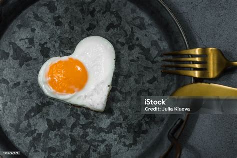 기치 빈티지 팬에 수제 계란 후라이와 어두운 배경에 세련된 칼 붙이 하트 모양의 노른자 위에서 본 모습 텍스트 공간을 복사합니다 0명에 대한 스톡 사진 및 기타 이미지