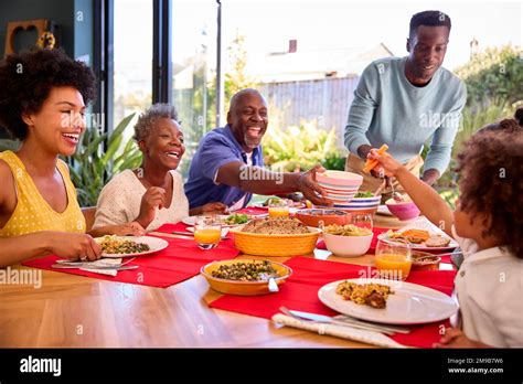 Multi-Generation Family Sitting Around Table At Home Enjoying Meal Together Stock Photo - Alamy