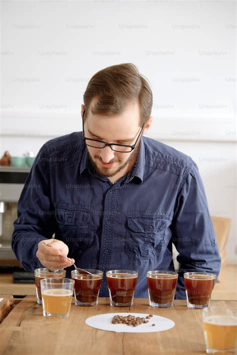 유리 컵에서 갓 내린 커피를 시음하는 남자의 초상화 숟가락을 사용하여 바로스타에 대한 커피 커핑 테스트에서 커피 맛과 풍미를