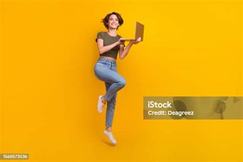 반짝이는 사랑스러운 숙녀 착용 카키색 티셔츠 점프 통신 현대 장치 격리 된 노란색 배경의 전체 길이 사진 노트북에 대한 스톡 사진 및 기타 이미지 Istock