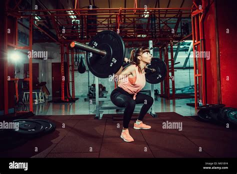 Gorgeous Young Fitness Woman Crouch And Doing Squad Exercise With A Bar