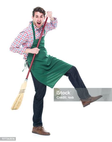 전체 길이 1 인 전면 2029 세 성인 잘 생긴 젊은 남자 남성 댄스 화이트 배경 착용 깅감 청바지 앞치마 앞에서 웃고 있는 행복 쾌활 하 고 빗자루를 들고 20 29세에