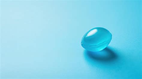 Blue Gel Capsule Resting On A Textured Aqua Surface Under Soft Lighting