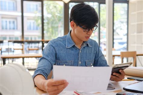 Architect And Engineer Reviewing Blueprints And Using A Tablet In A Modern Office Stock Image