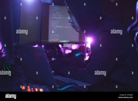 Side View At Unrecognizable Cyber Security Hacker Wearing Hood While Working On Programming In