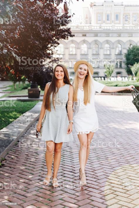 두 행복한 미소 소녀는 햇볕이 잘 드는 도시에서 걷고있다 아름다운 금발과 갈색 머리 는 거리를 걷고 학생 여행자 2명에 대한 스톡 사진 및 기타 이미지 Istock