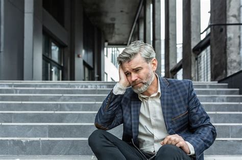 Empresário De Cabelos Grisalhos Sentado Triste Na Escada Do Lado De