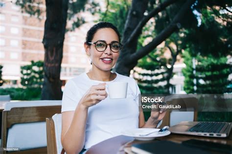 거리 카페에서 노트북으로 작업하는 동안 뜨거운 커피를 마시는 안경을 쓴 웃는 여자 35 39세에 대한 스톡 사진 및 기타 이미지 35 39세 경영자 긍정적인 감정