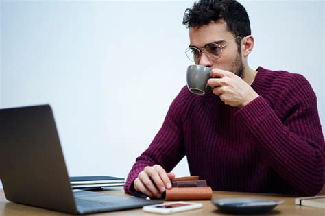 사무실 인테리어에 앉아 무선 인터넷에 연결 하는 랩톱 컴퓨터에서 작업 하는 동안 마시는 커피 광 안경에 지적인 학생을 집중 우주 배경 복사 Cd 라이터에 대한 스톡 사진 및