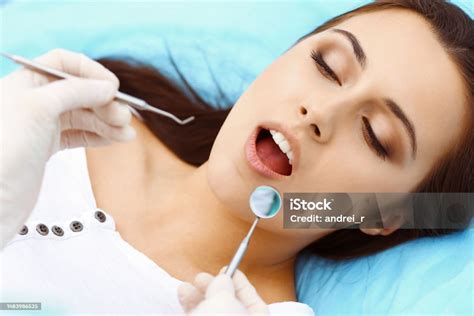 젊은 여성 환자는 치과 의사 사무실 방문 건강 한 바로 화이트 치아 치아에서 일 하는 의사는 동안 구강 검 진 기간 동안 오픈 입으로 치과 자에 앉아 아름 다운 여자 18