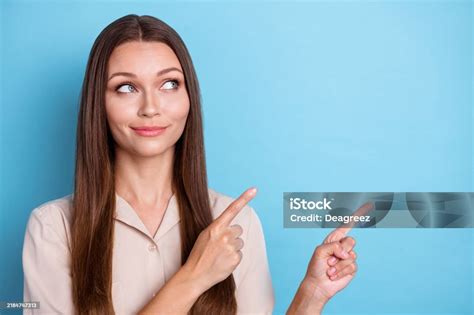 파란색 배경에 고립 된 빈 공간을 나타내는 베이지 색 셔츠를 입은 스트레이트 헤어 스타일을 가진 멋진 귀여운 화려한 여자의