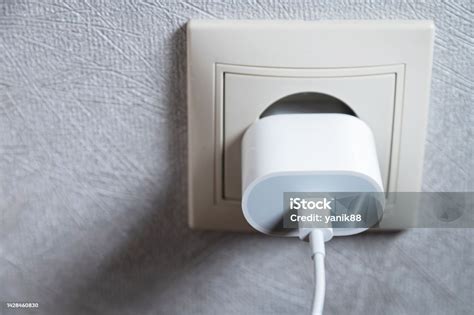 분홍색 벽에 전기 소켓 검은색 와이어 플러그가 연결되어 있습니다 스튜디오 아파트의 개조 된 배경 빈 복사 공간 단일 흰색 플라스틱 소켓 0명에 대한 스톡 사진 및 기타