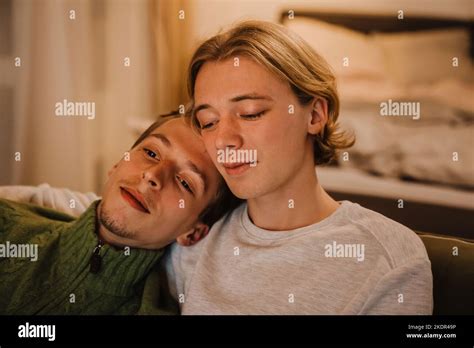 Young Gay Couple Hugging And Resting On Couch While Watching Tv At Home