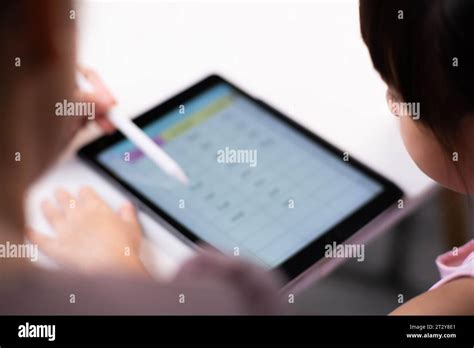Glückliche kleine asiatische Tochter mit ihrer Mutter über ein digitales Tablet spricht um