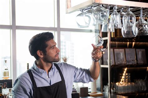 젊은 백인 남자는 바텐더를 들고 카운터에서 전문가 초상화 잘 생긴 남성 준비 유리 또는 와인 잔 바텐더가 레스토랑에서 자신감있게